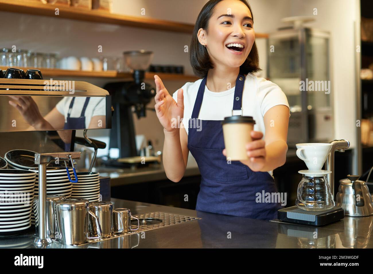 Portrait of smiling asian girl barista, giving out order in cafe ...