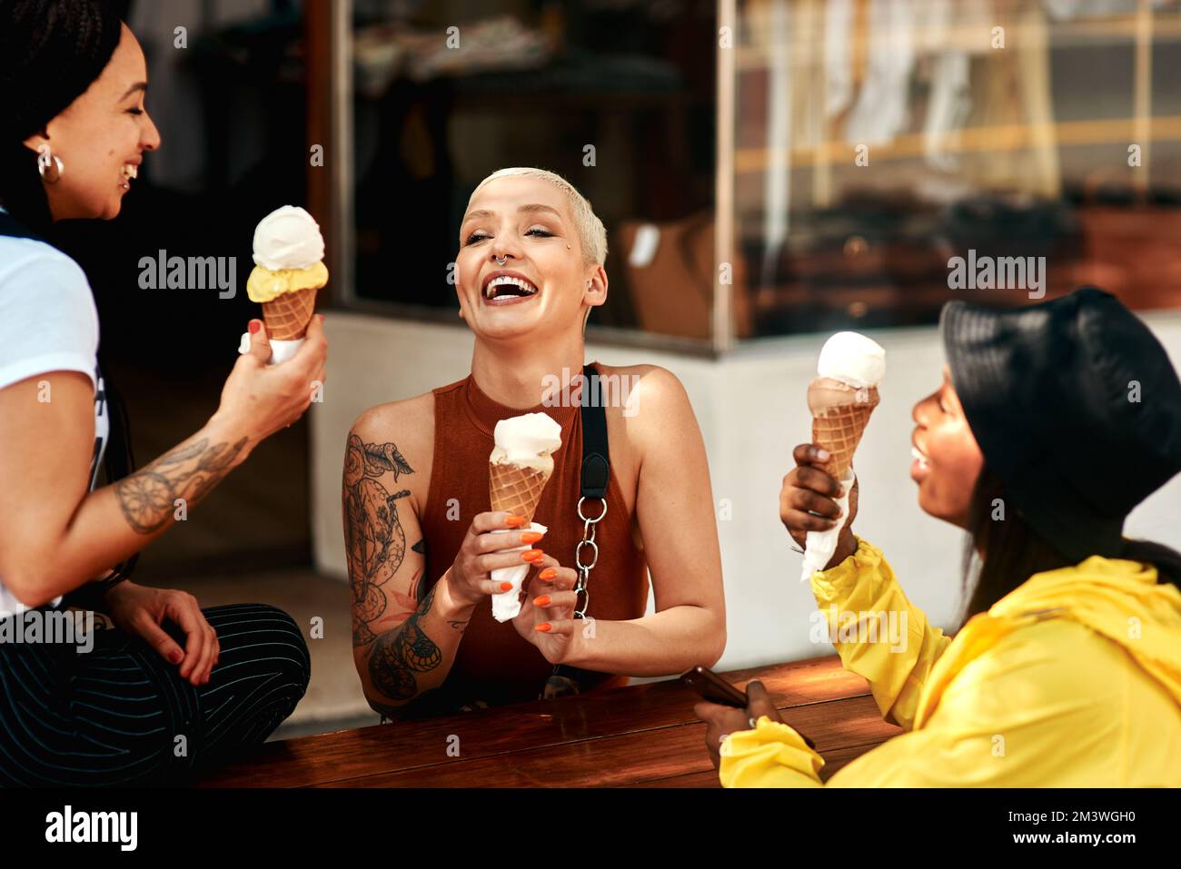 Ice cream and laughs. three friends enjoying ice cream cones while out ...