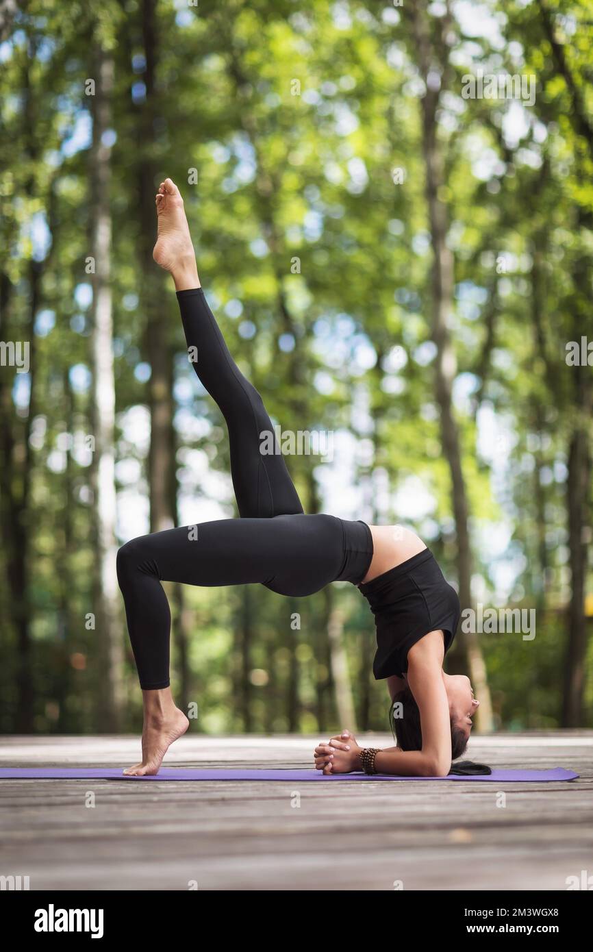 An attractive young woman practicing yoga, performs a leg-lifting ...
