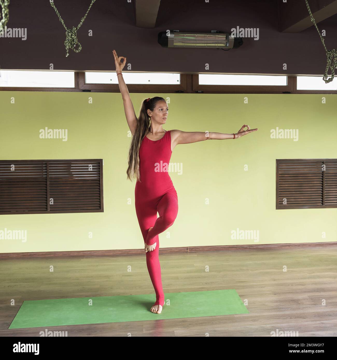 A woman leading a healthy lifestyle, performs a Vikshasan exercise with ...