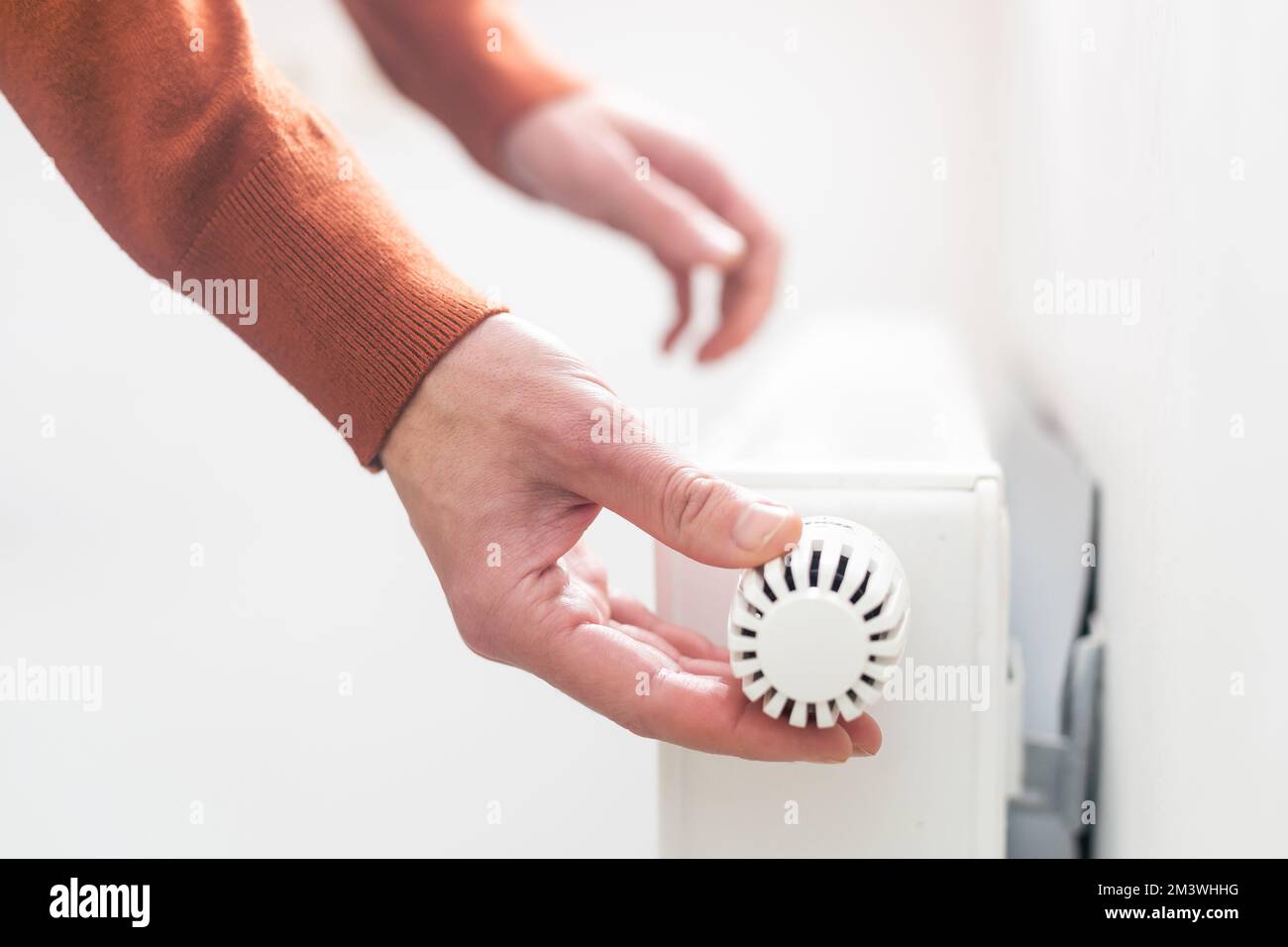 hand adjusting radiator temperature using thermostat. Home with central ...