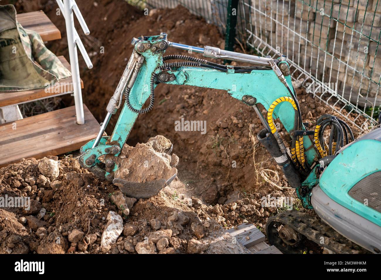 Mini excavator digs a trench to lay pipes. Close up of an excavator ...