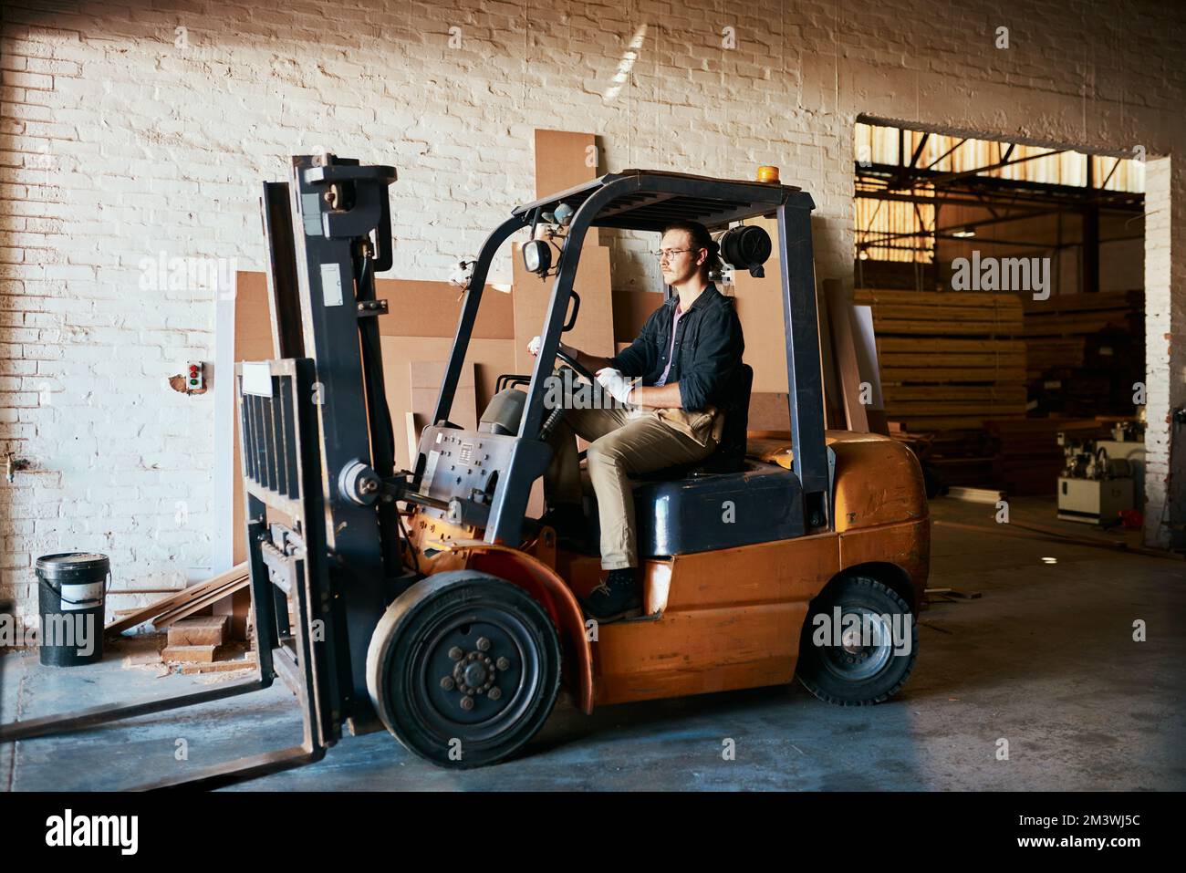 Every warehouse needs a forklift. a young male warehouse worker driving ...