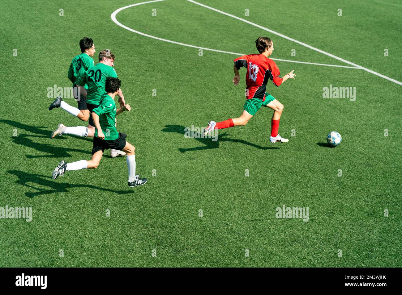 The high-angle view of a single soccer player chased by three ...
