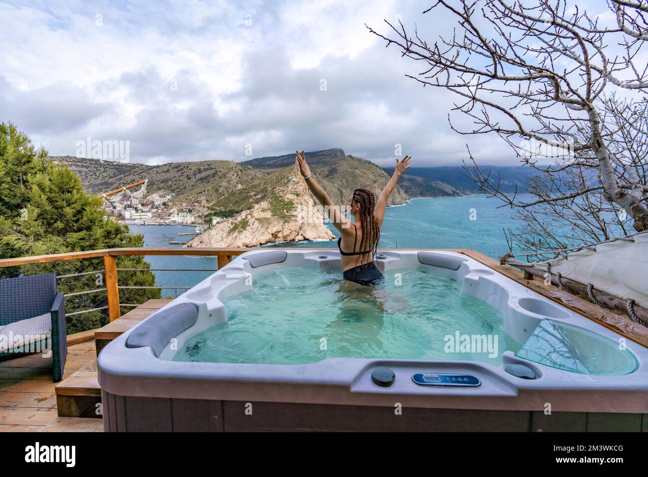 Outdoor jacuzzi with mountain and sea views. A woman in a black ...