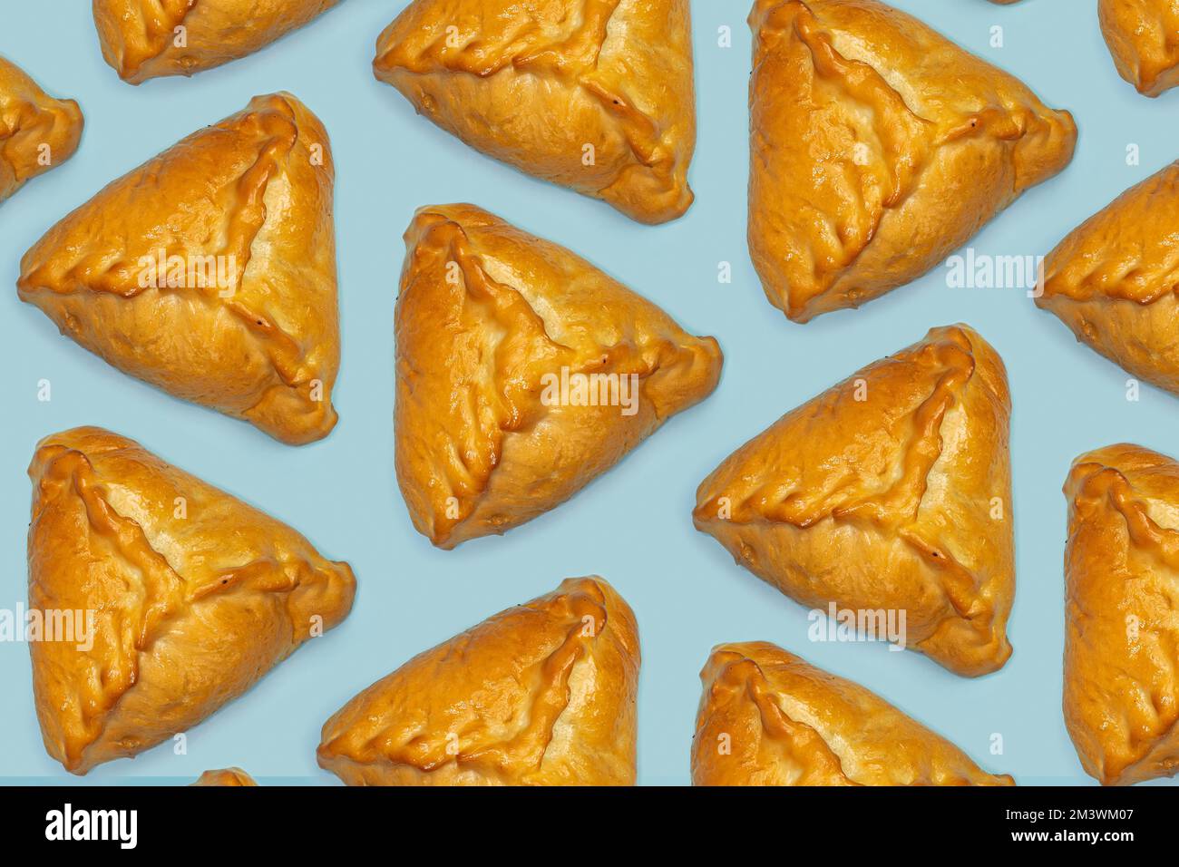 kulebyak or khachapuri. triangular pie with filling on a blue table ...