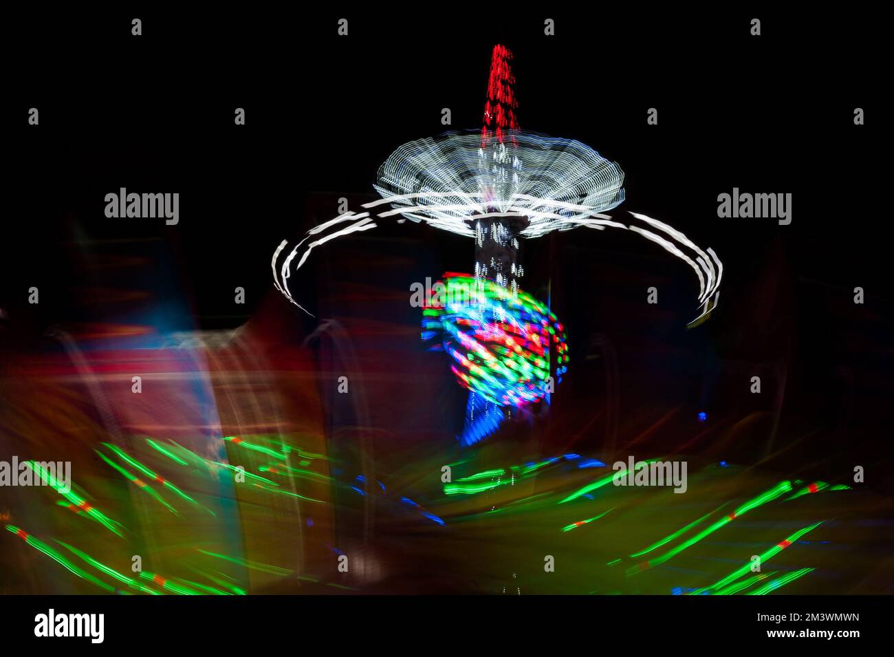 Rotating illuminated attraction in amusement park at night. Motion ...