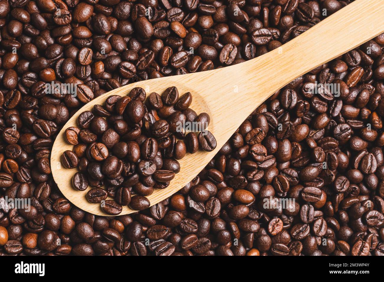 Wooden spoon with roasted coffee beans on a background of coffee beans ...