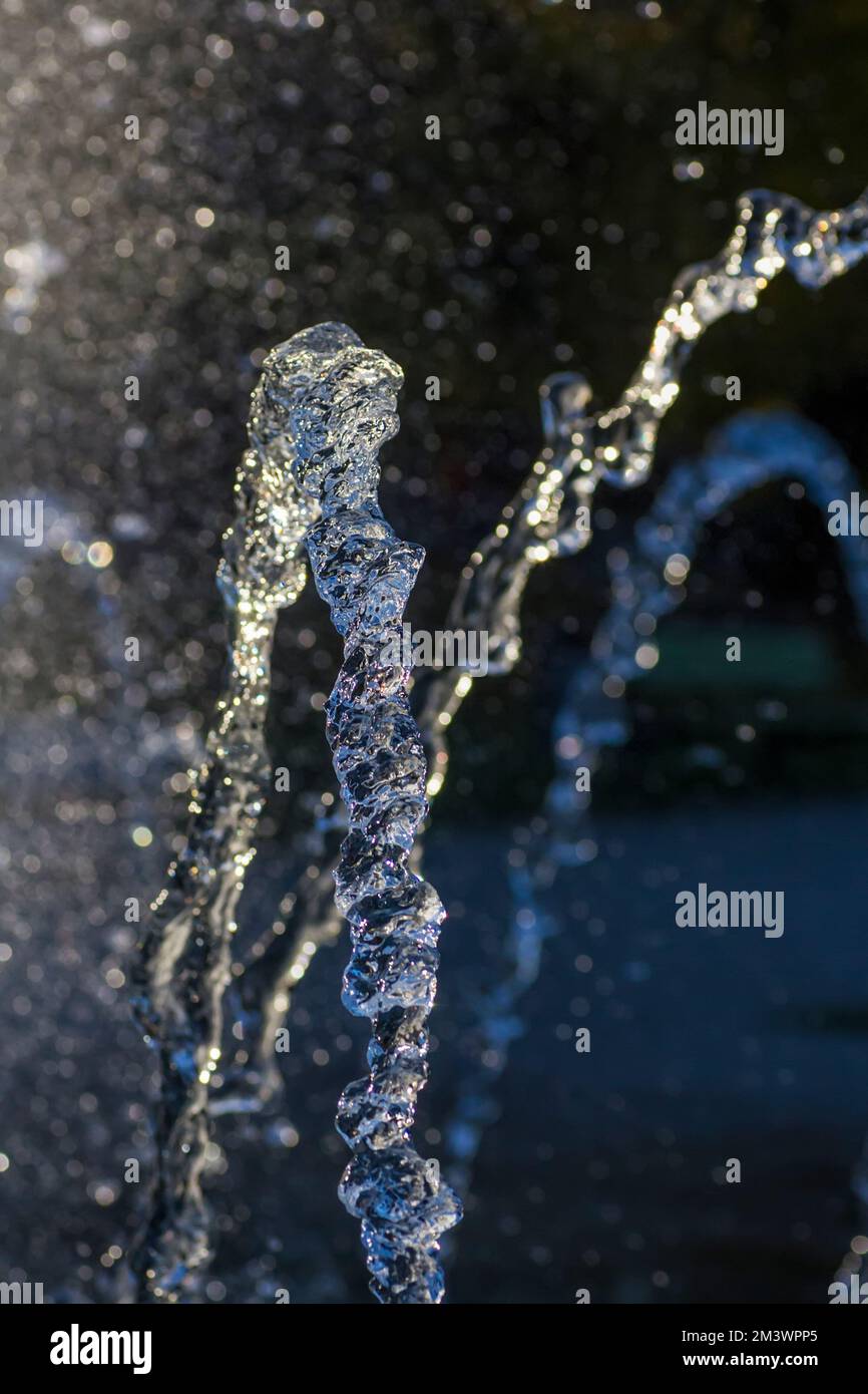 A vertical shot of a water fountain splashing outdoors in daylight on a ...