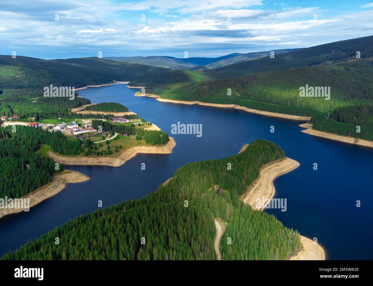 An aerial shot of Oasa lake in Romania surrounded by fir forest trees ...