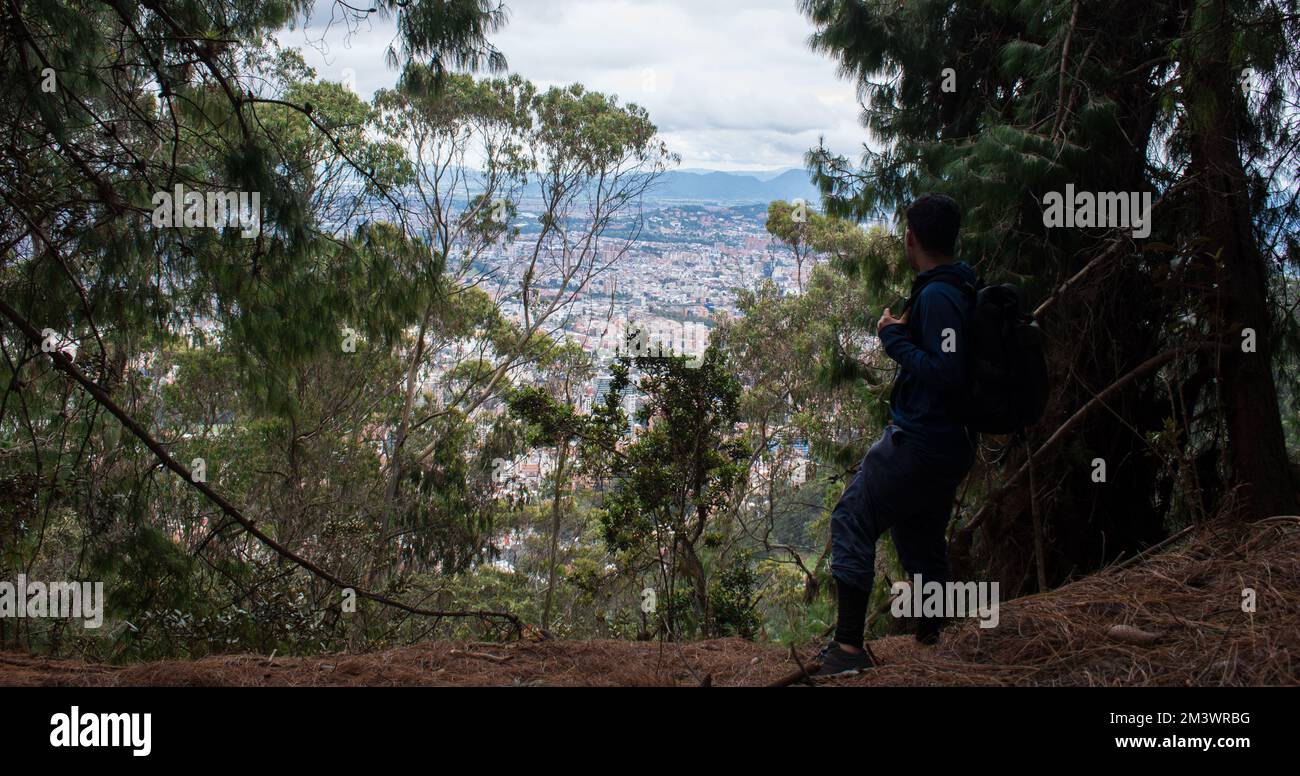 A man standing on the top of the hill and looking at the cityscape ...