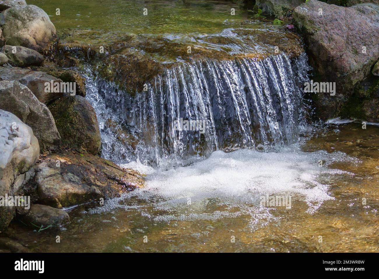 A scenic view of a small cascade on the stream in the woods in daylight ...