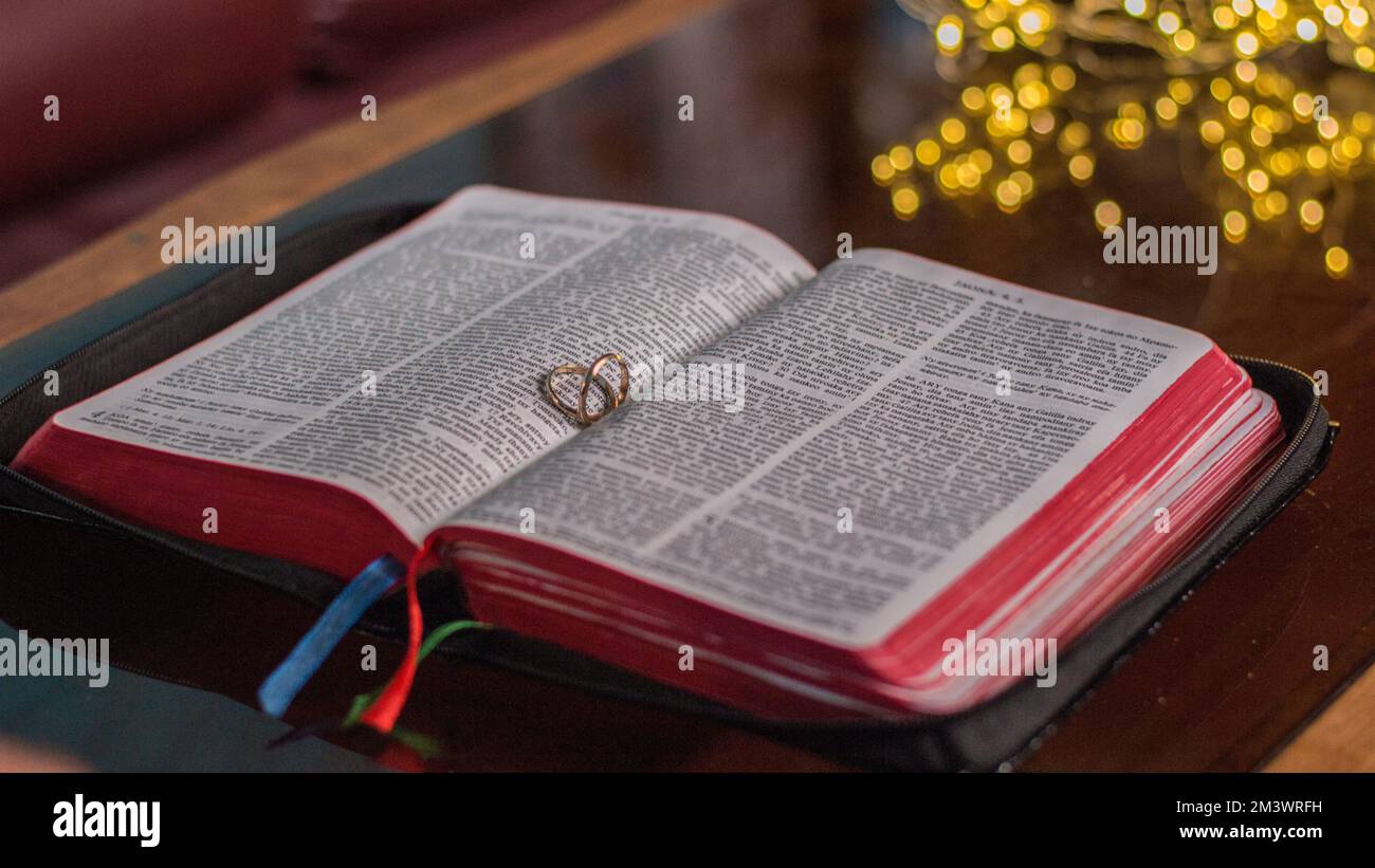 Two Wedding rings on a Bible with bokeh background Stock Photo - Alamy