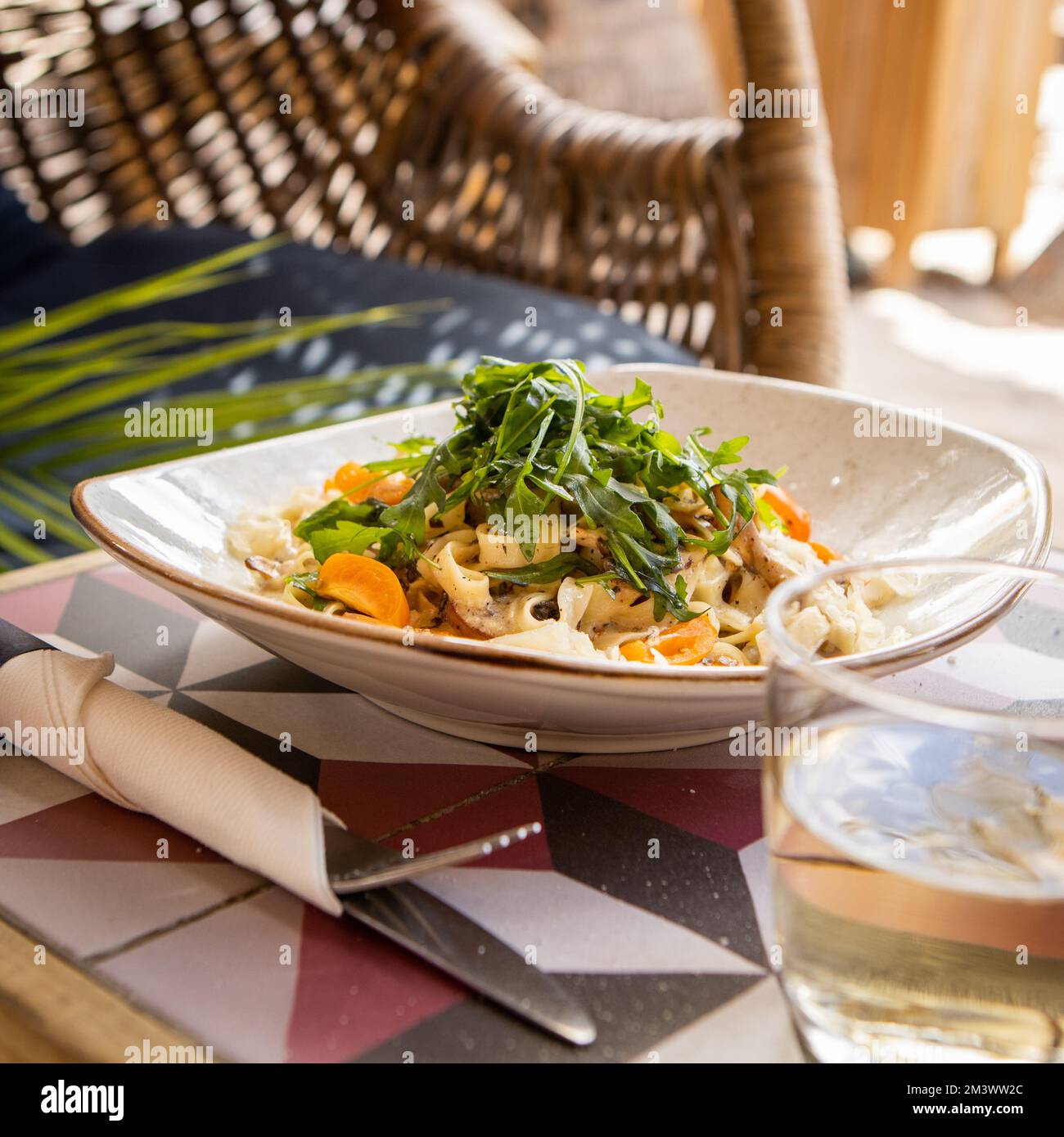 Tasty Pasta with cheese slices and herbs on white plate on the table ...
