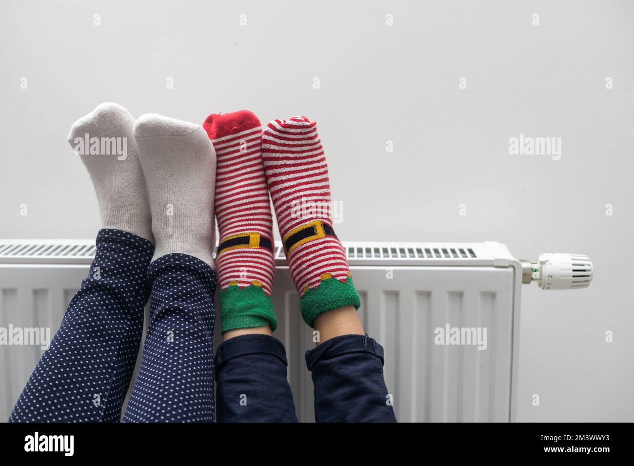 legs of mother and daughter near the radiator Stock Photo - Alamy