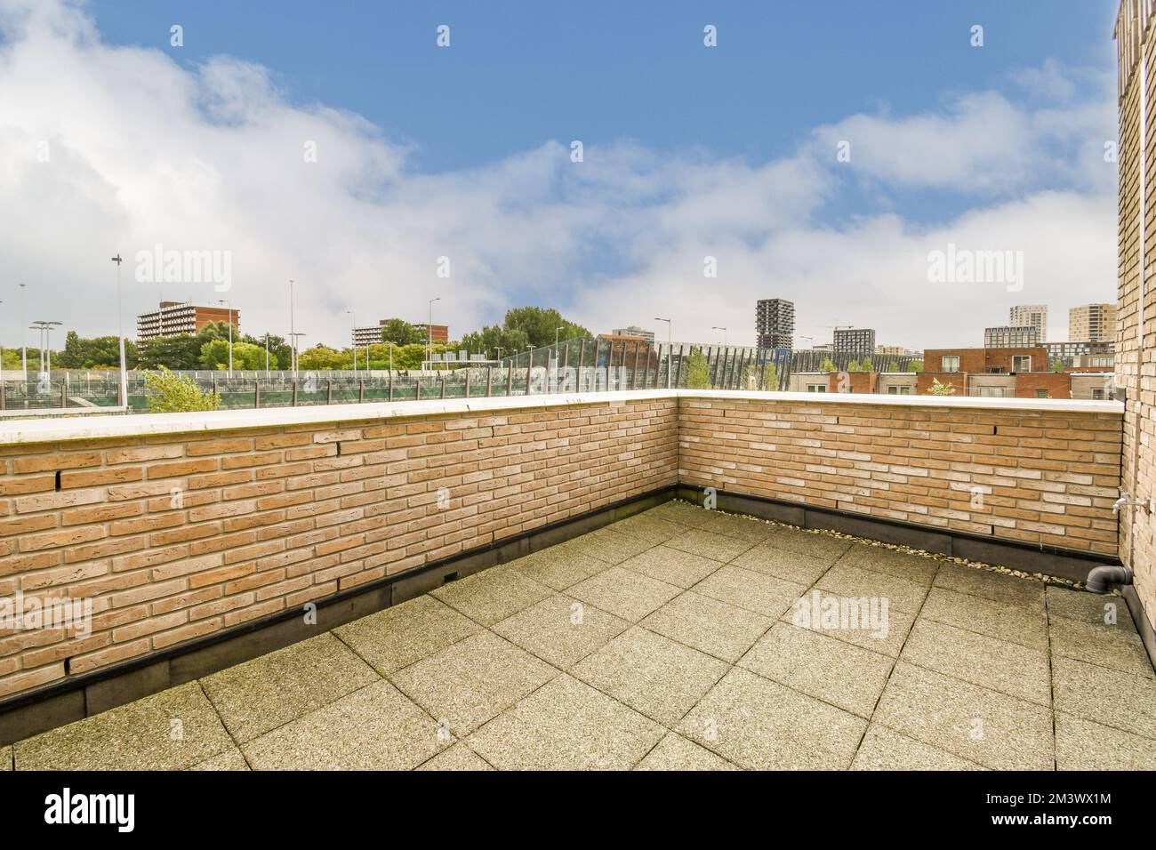 a brick wall and some buildings in the distance with blue skies above ...