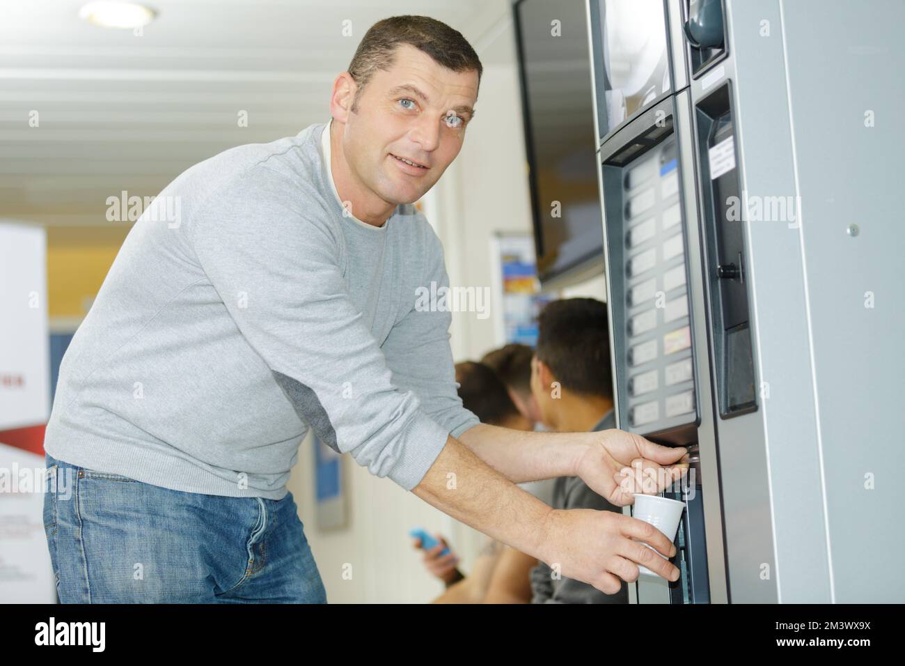 portrait of man getting drink from vending machine Stock Photo - Alamy