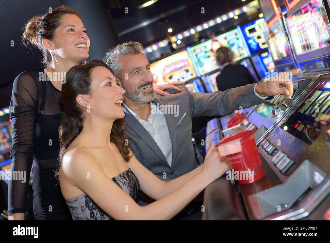 group of friends playing slot machines Stock Photo - Alamy