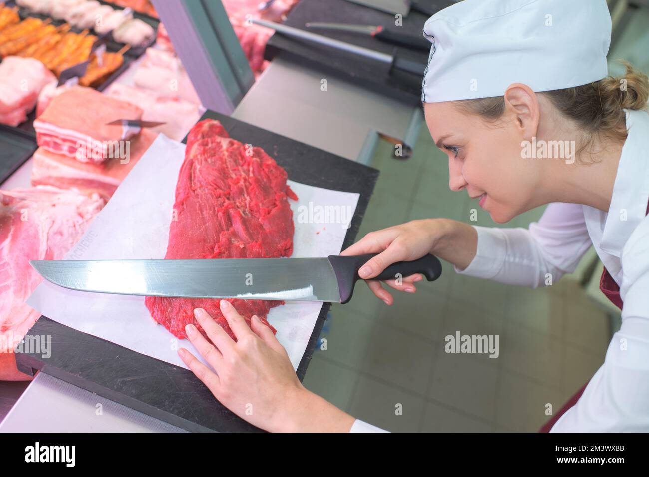 female butcher cutting beef with large knife Stock Photo - Alamy