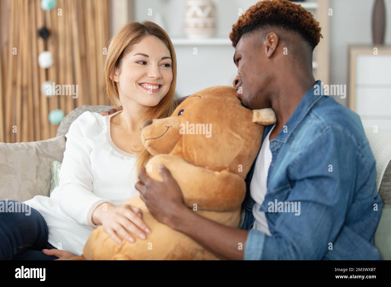 young couple sat with giant teddy bear Stock Photo - Alamy