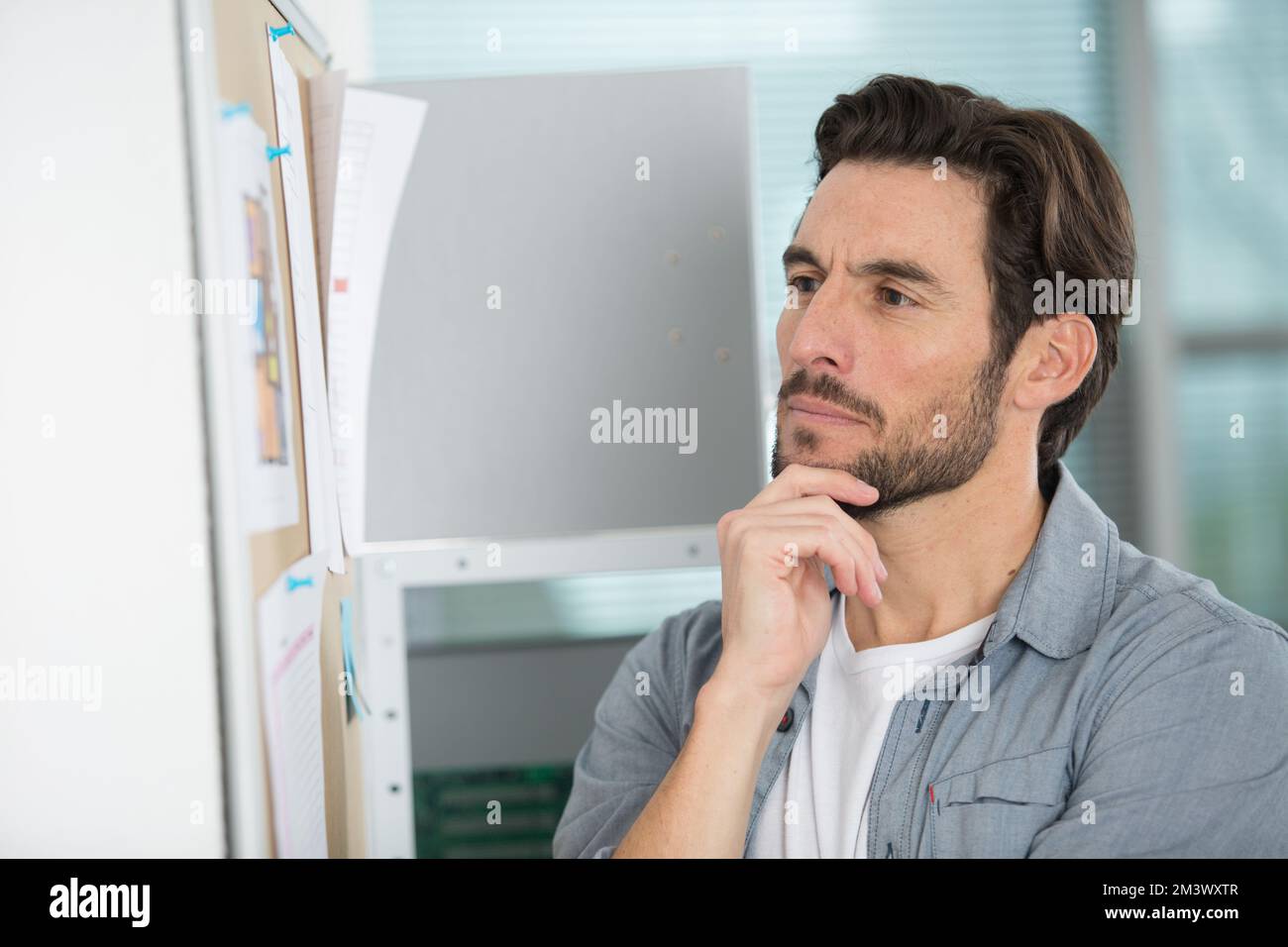man deep in thought by a notice board Stock Photo - Alamy