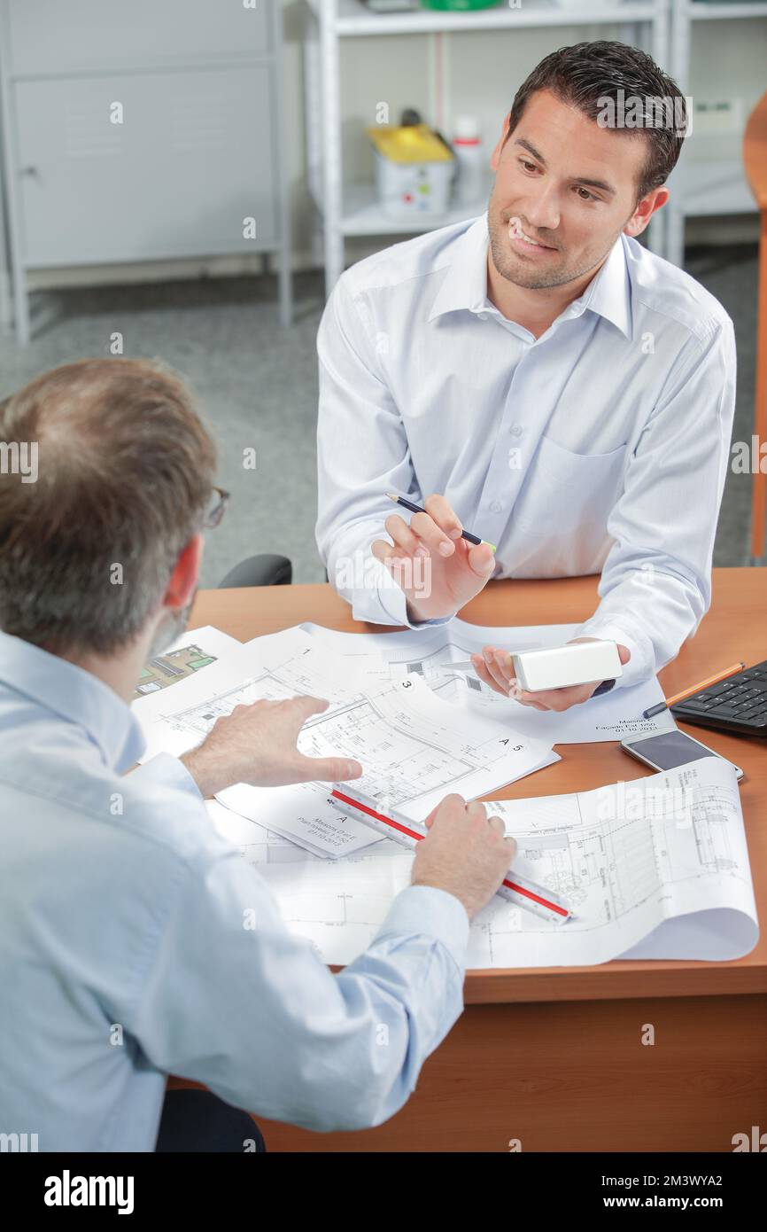 Two men in meeting, blueprints between them Stock Photo - Alamy