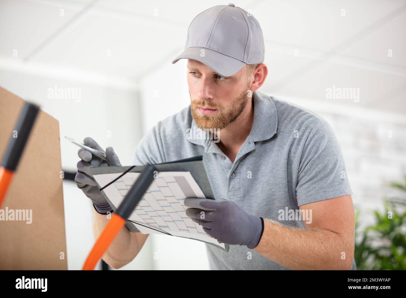 delivery man checking list on clipboard indoors Stock Photo - Alamy