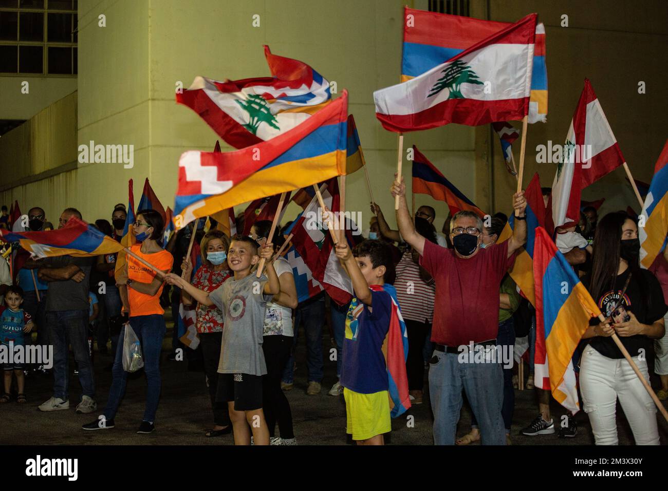 A crowd of people holding flags at a meeting to support Artsakh during ...