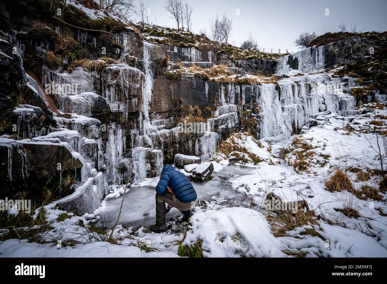 People look at icicle formations a frozen waterfall in the Brecon Beacons National Park, Wales ...