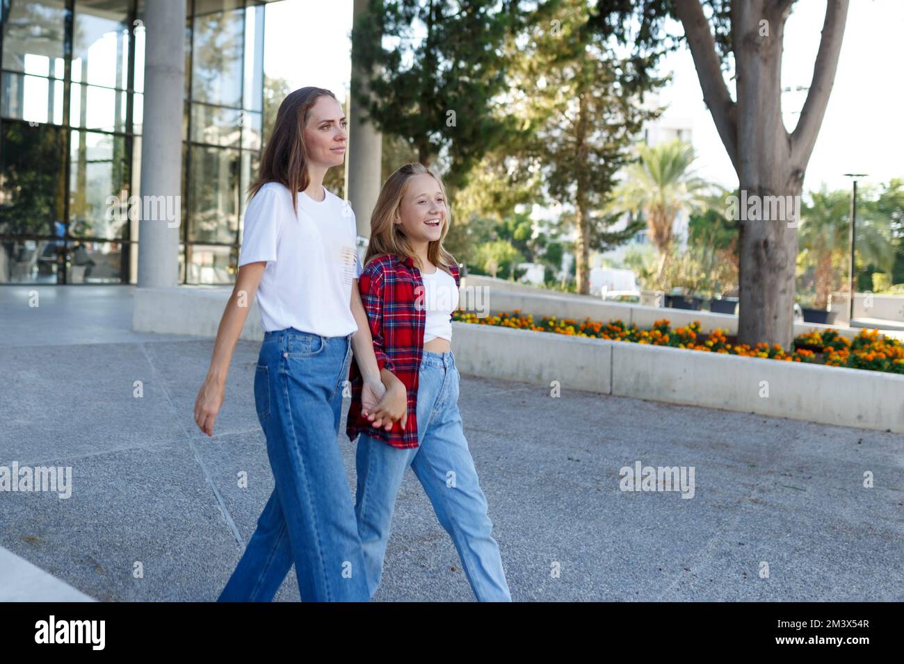 Woman walking and chatting with daughter schoolgirl after school ...