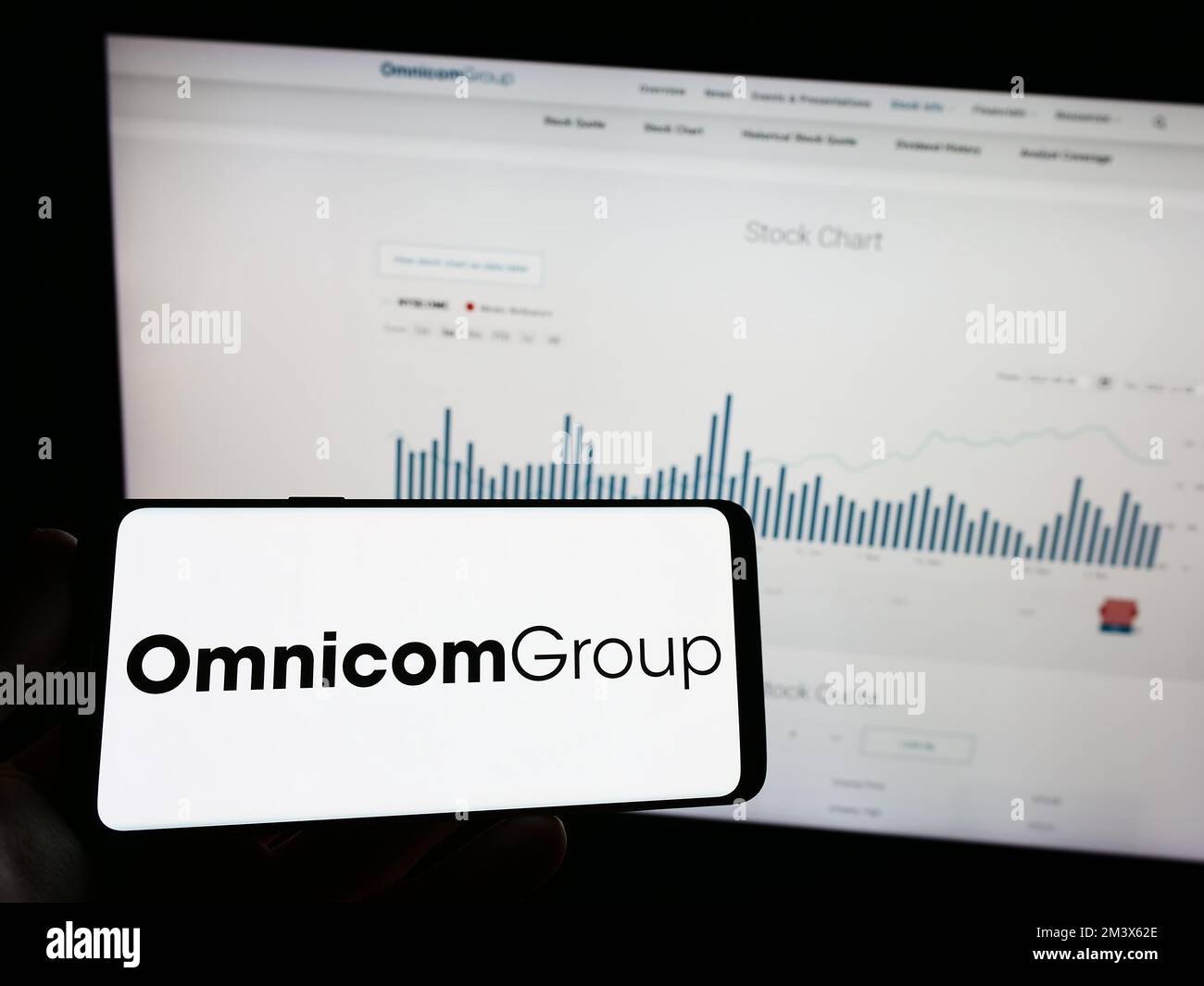Person holding mobile phone with logo of American media company Omnicom Group Inc. on screen in ...