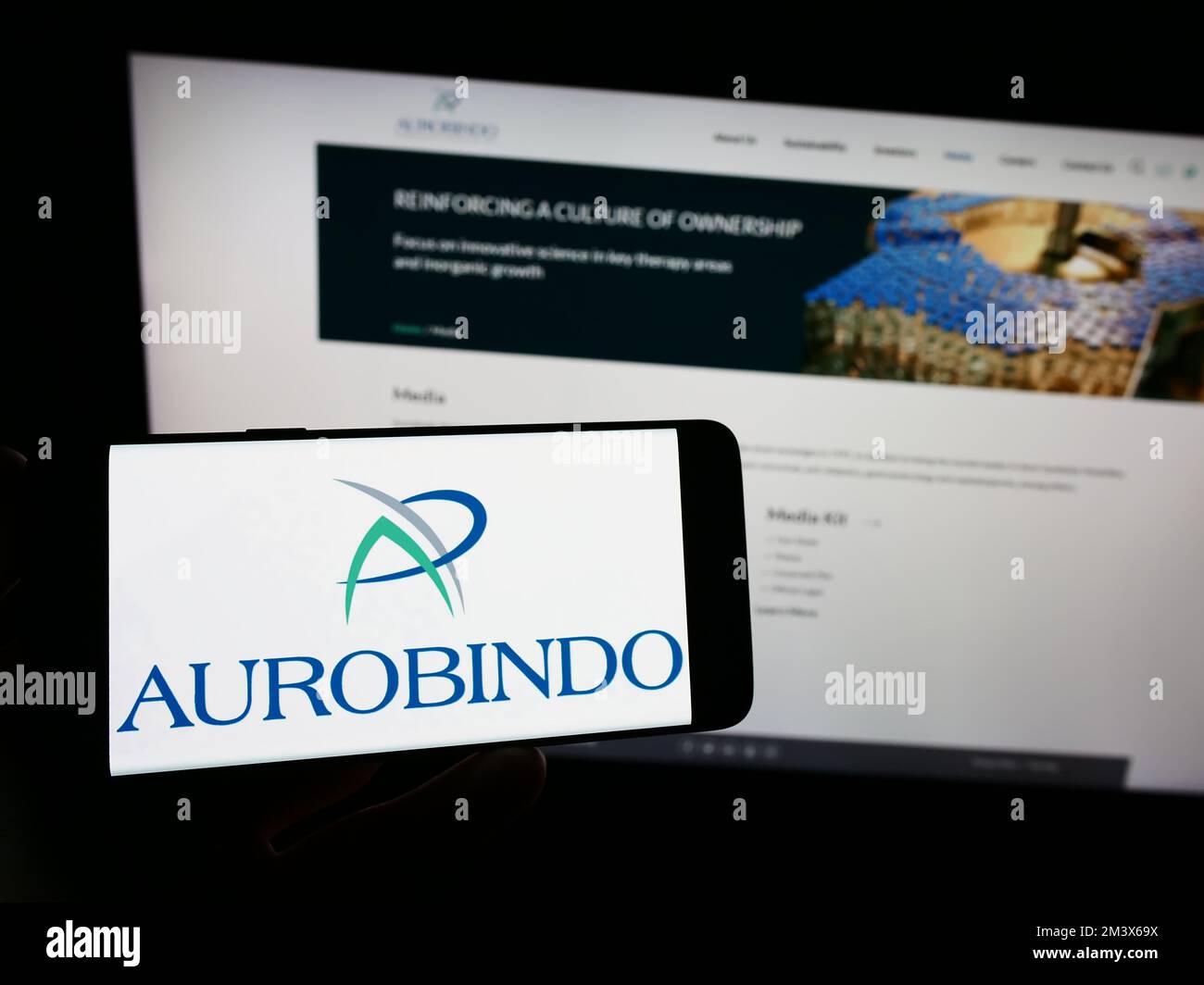 Person holding cellphone with logo of Indian company Aurobindo Pharma ...