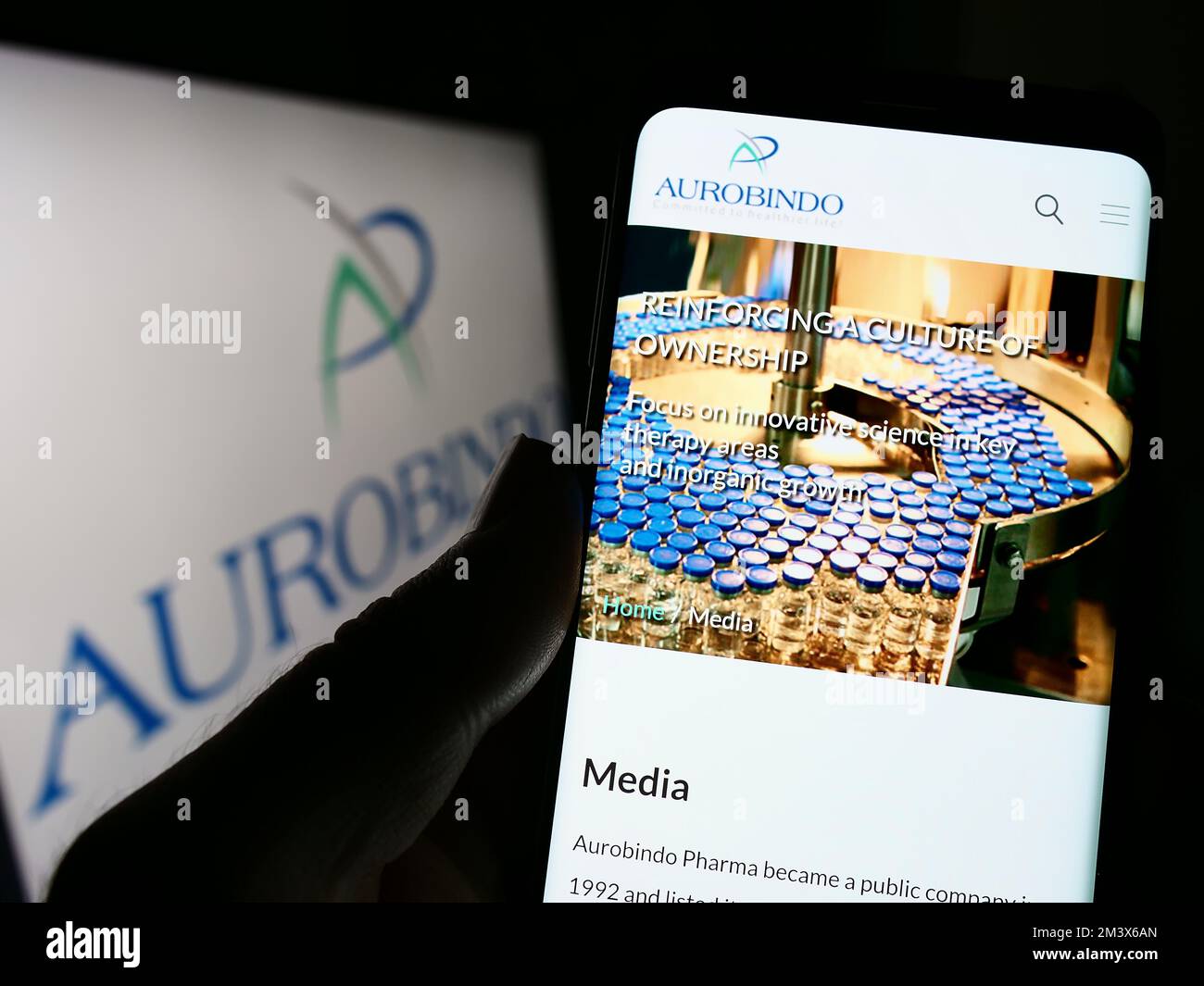 Person holding cellphone with webpage of Indian company Aurobindo ...