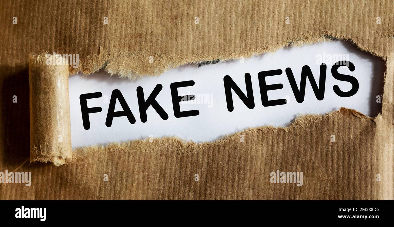 FAKE NEWS word written under torn paper Stock Photo - Alamy