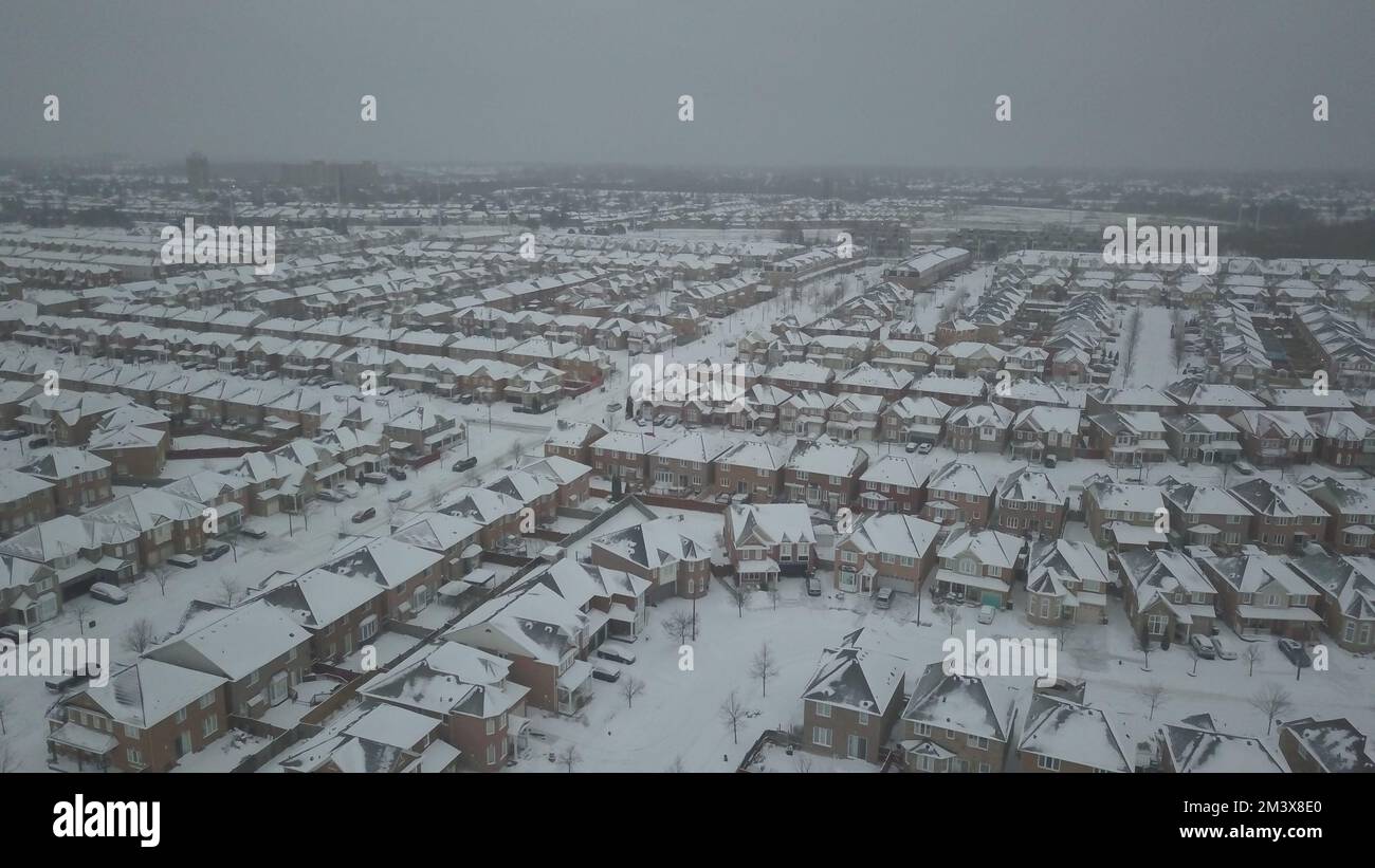 A high angle shot of several houses, a road and cars during winter ...