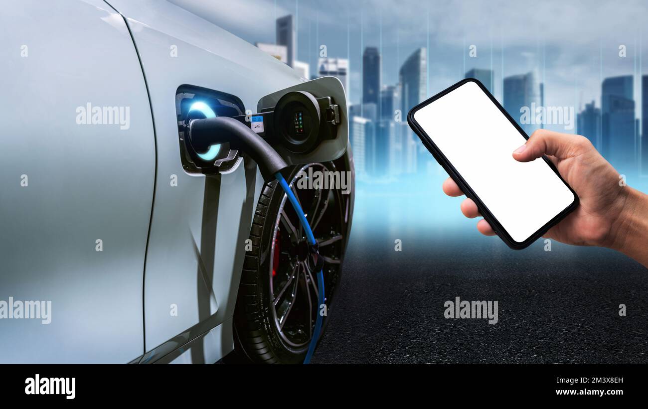 Hand holding smartphone with power supply connected to electric vehicle ...
