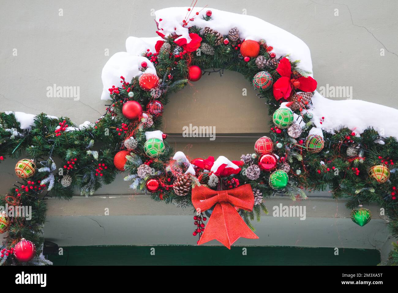 Building facade decorated with snow covered Christmas wreath, fir tree ...