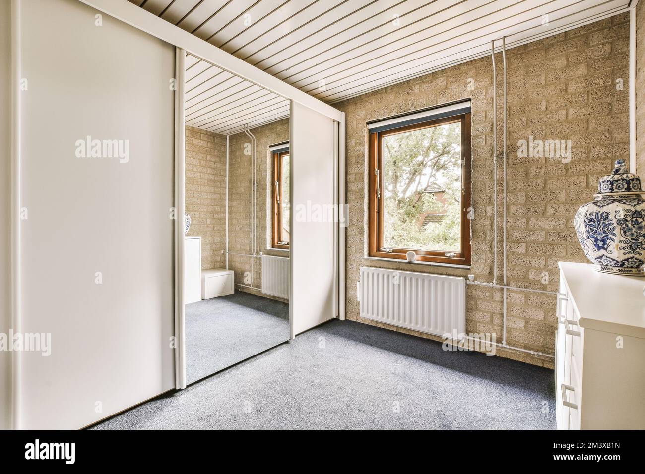 a room with an open door and a vase on the floor in front of the doorway, next to a toilet Stock ...