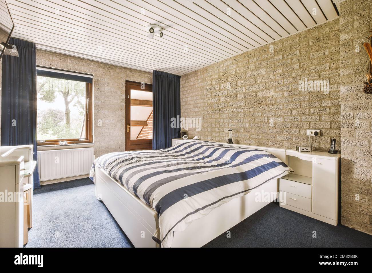 a bedroom with a brick wall and blue rugs on the floor in front of the ...