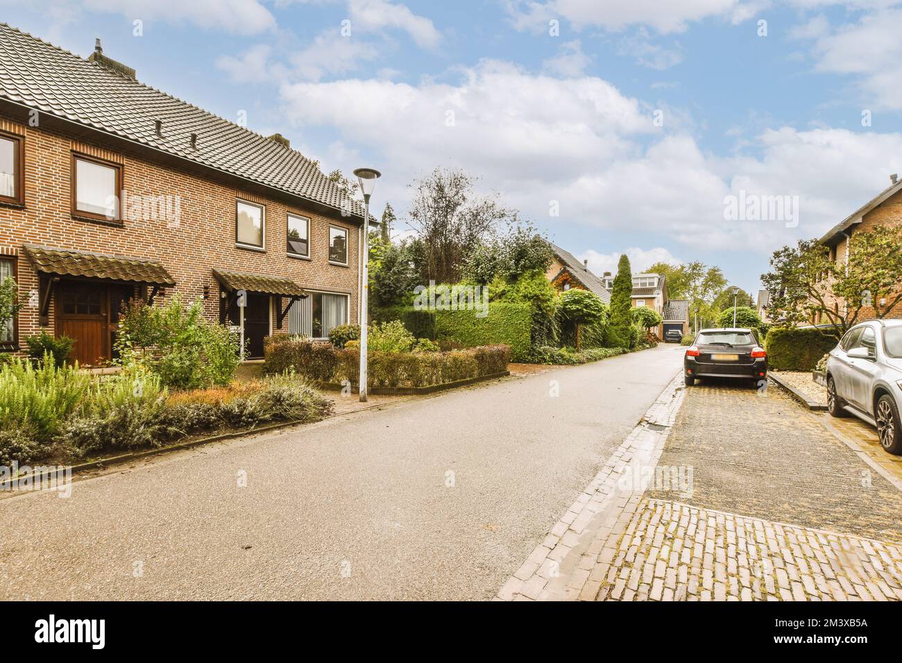 a street with cars parked on the side and houses in the back, some ...