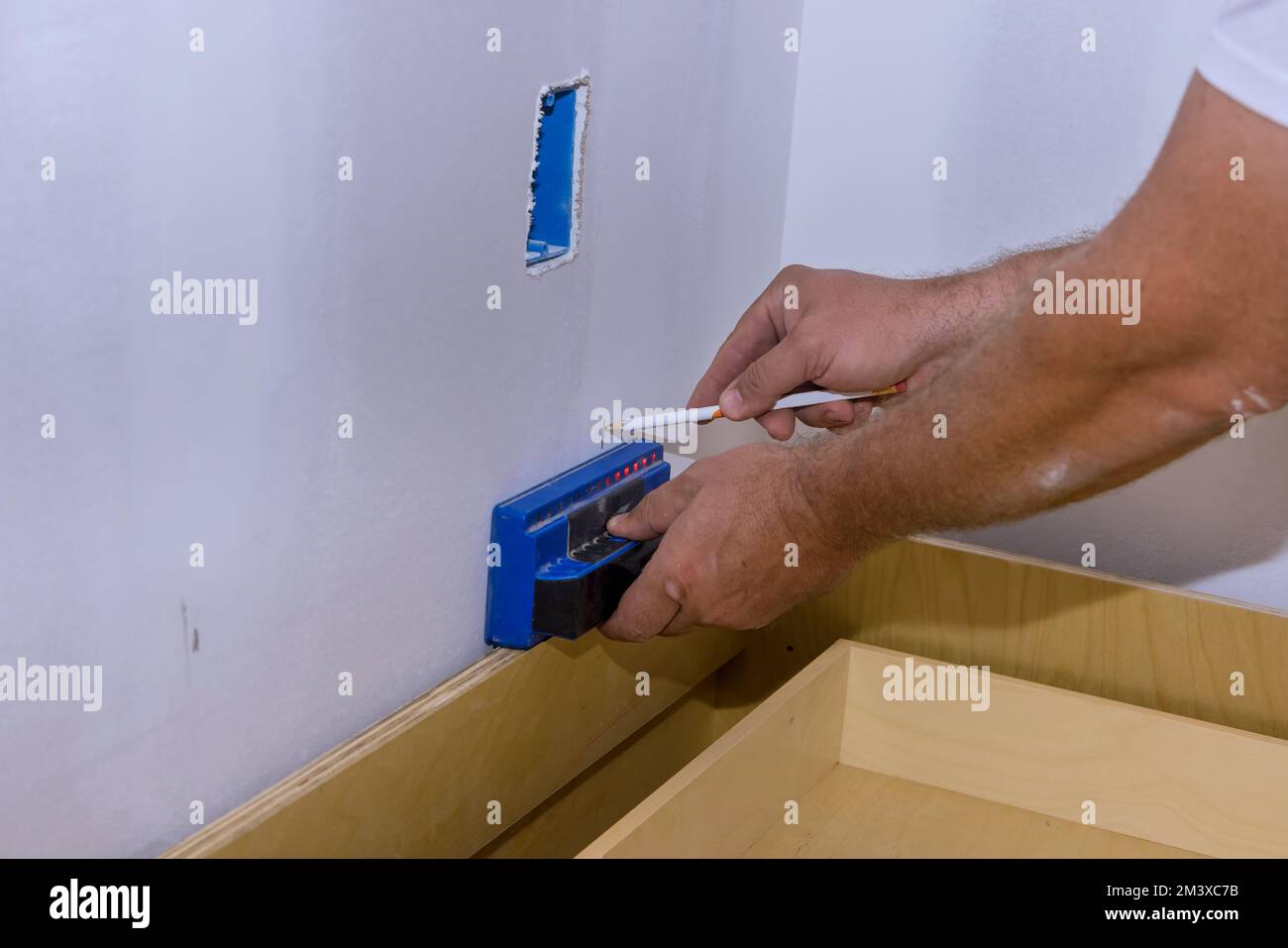 Using digital detector worker scans wall for wooden beams on wall with ...