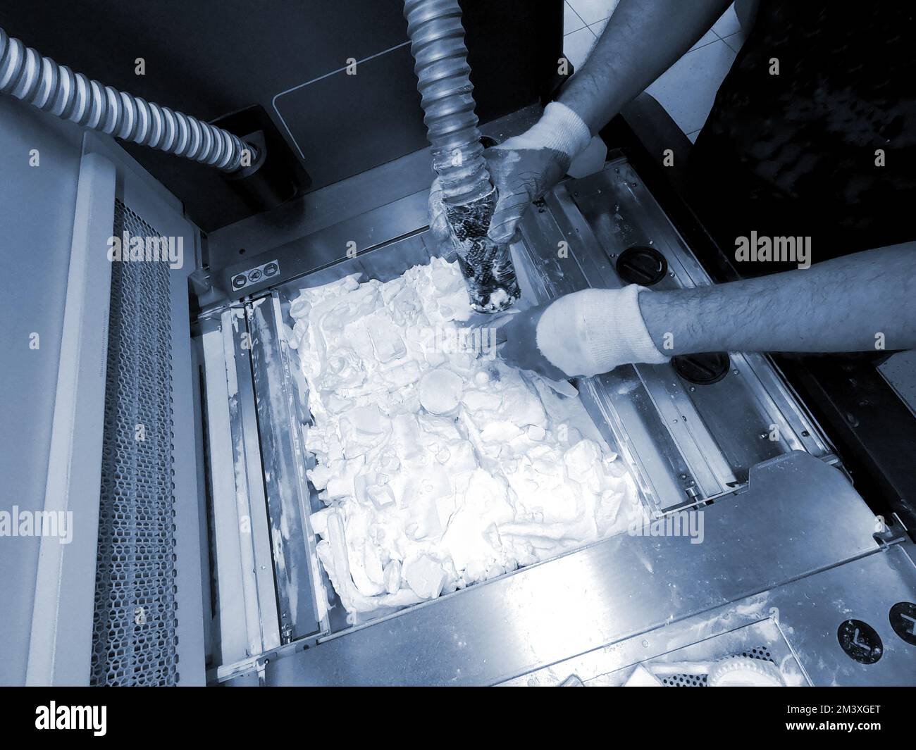 Mane taking out models from white polyamide powder in working chamber ...