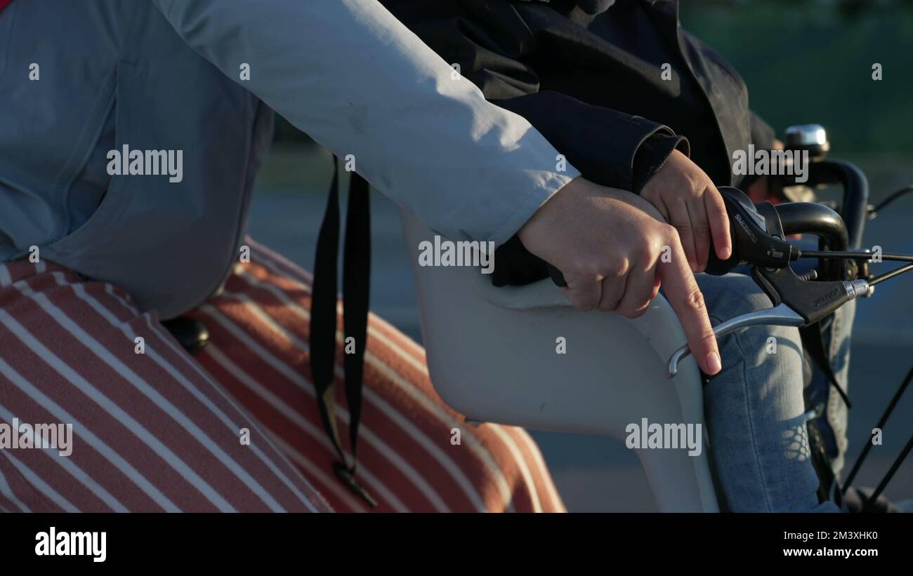 Closeup mother hands holding bicycle handle with child seated in front ...
