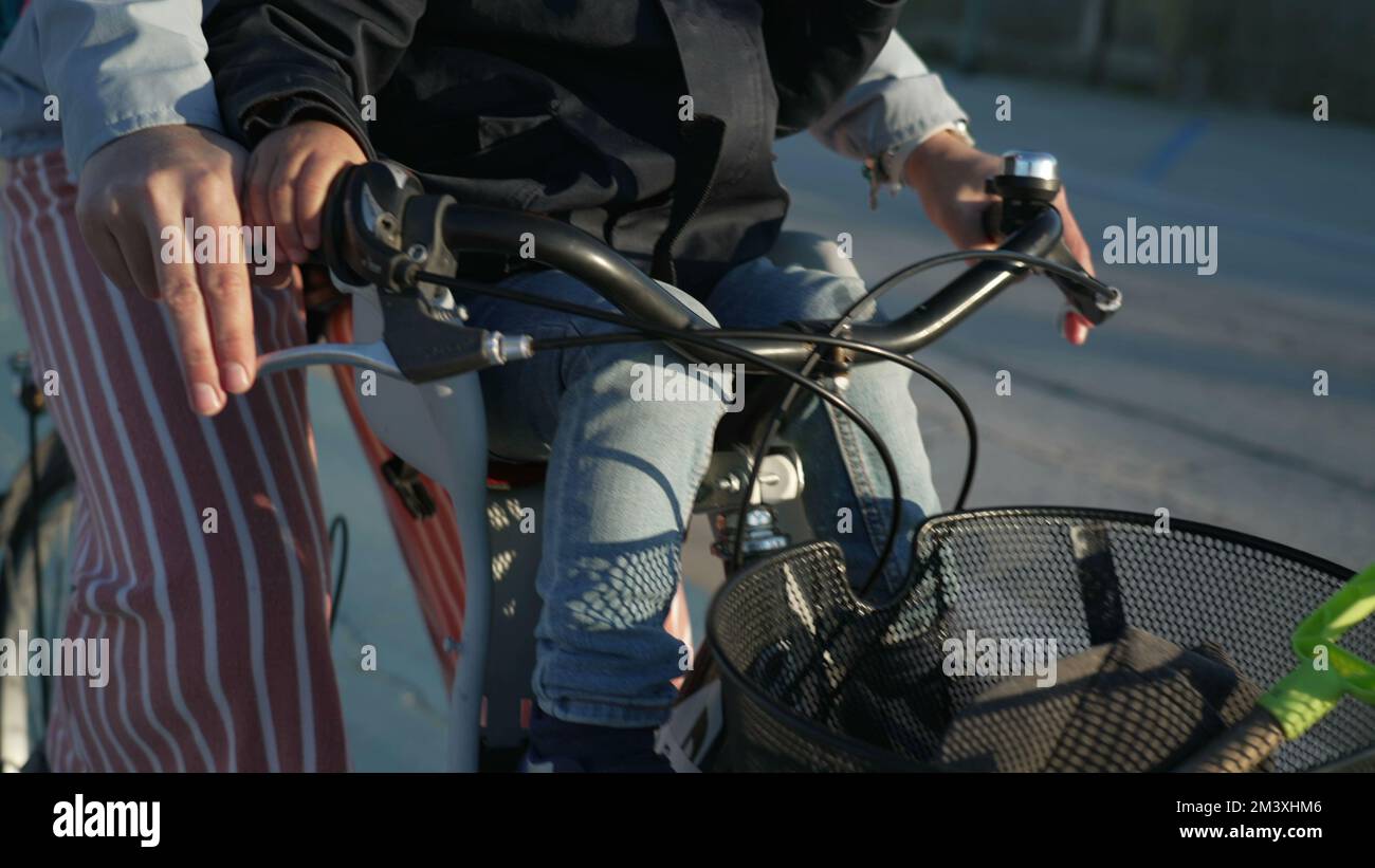 Closeup mother hands holding bicycle handle with child seated in front ...