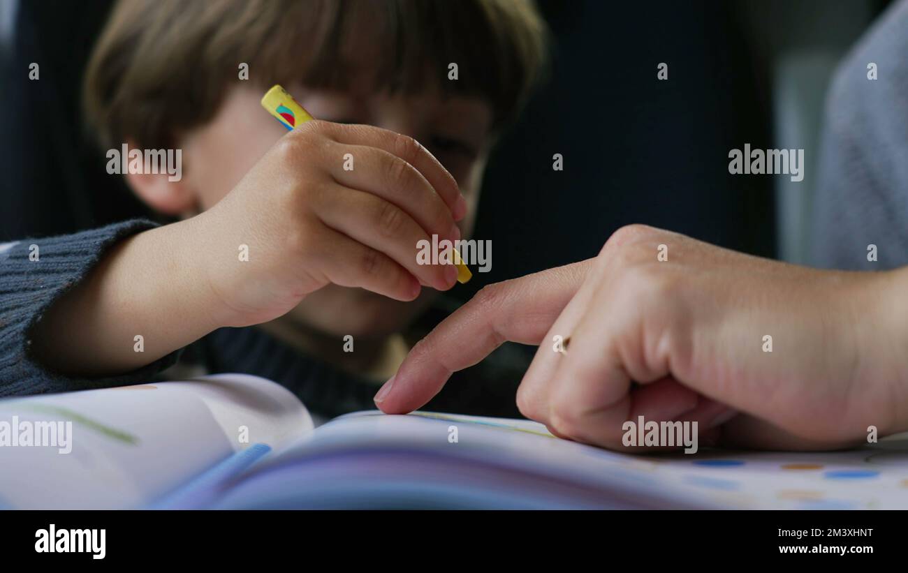 Child doing homework closeup face. Mother hand pointing at drawing ...