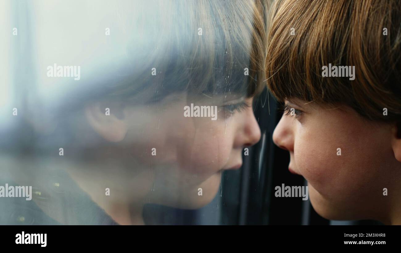One pensive child leaning on train window. Mirror glass reflection of ...