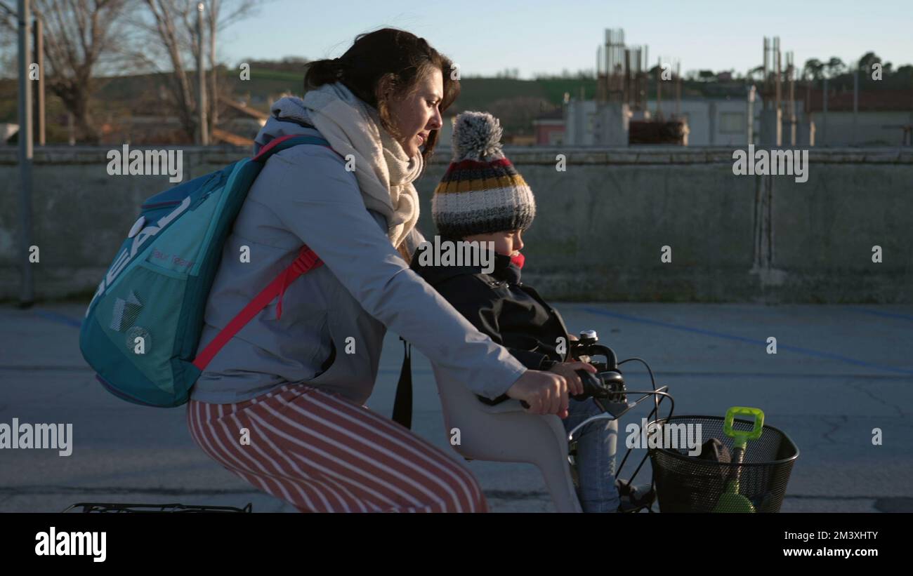 Mother rides bike with child in front during cold winter day with ...