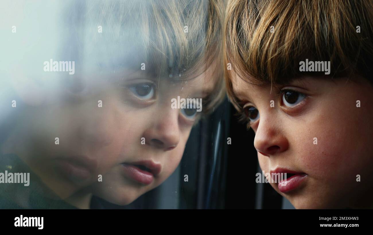 One pensive child leaning on train window. Mirror glass reflection of ...