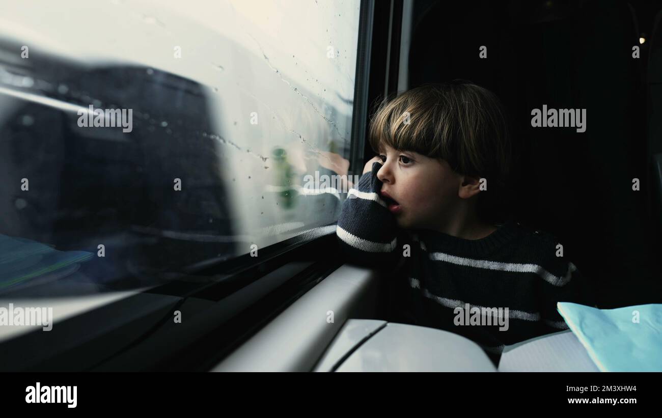 One sad little boy looking out train window in motion. Melancholic ...