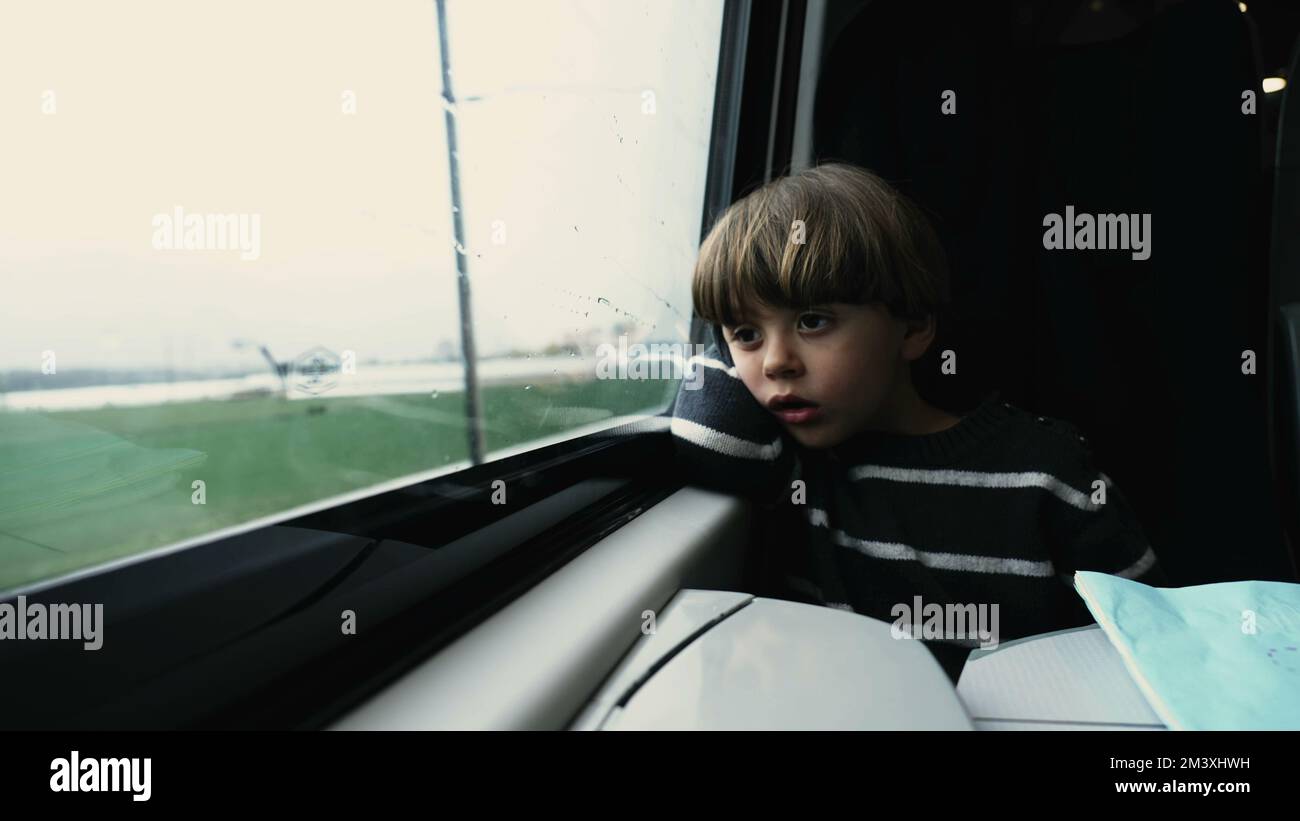 One sad little boy looking out train window in motion. Melancholic ...